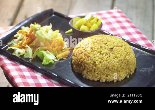 Plain bulgur rice with salad and pickles rotating on black plate in ...
