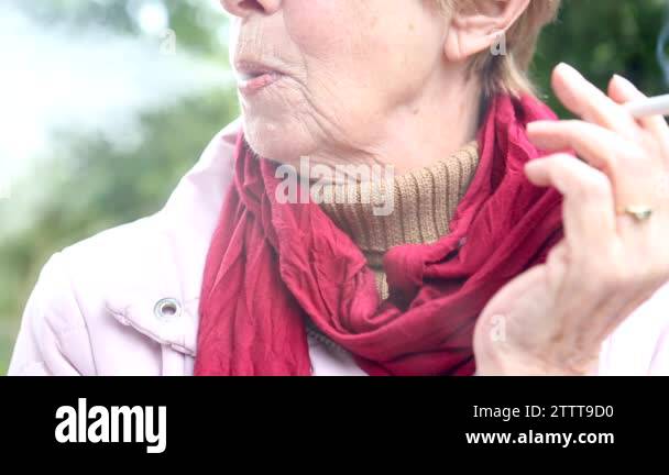 Cinemagraph of older woman standing outdoors and smoking a cigarette ...
