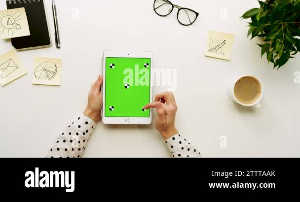 Top view on the office desk and white tablet computer with green screen ...