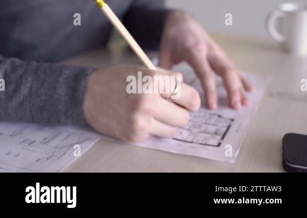 Male architect is making correction in building blueprints, close up ...