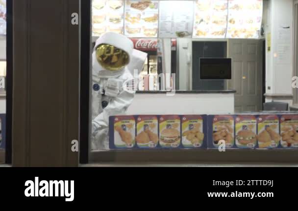 4K Astronaut in full space suit sweeping the floor in fast food shop ...