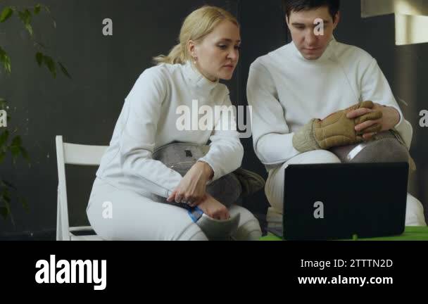 Two young fencers man and woman watching fencing tutorial on laptop ...