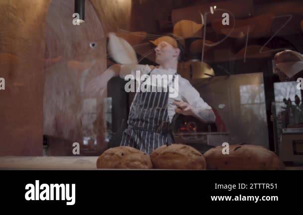 Young guy in chef uniform spinning and tossing pizza dough throwing it ...