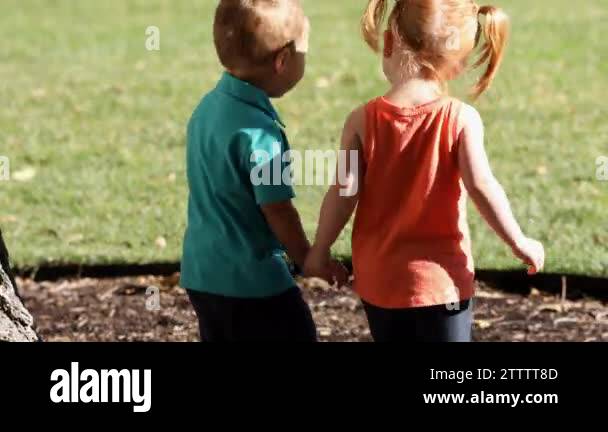 Two kids walking and holding hands as boy pulls his hand away but the ...