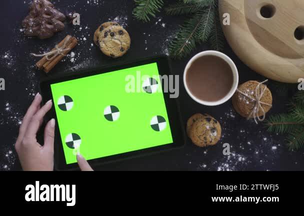 Table top view from above. Woman swipe, slide images to the left, than tapping on tablet green ...