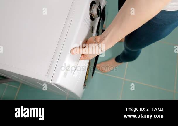 woman adding detergent to compartment in washing machine and closing ...