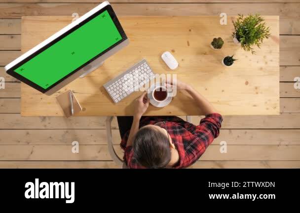 Casual woman drinking coffee in modern office room infront of computer ...