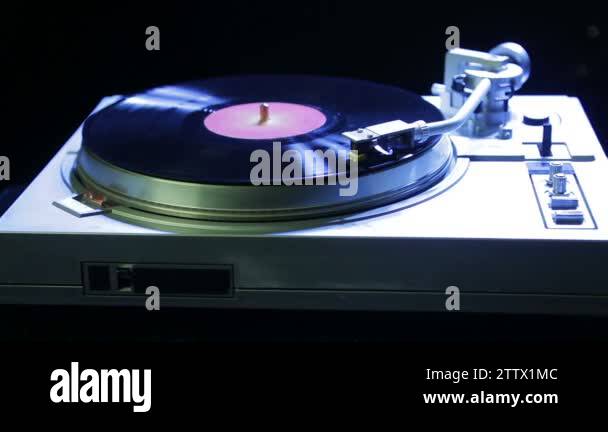 A female hand stops a turntable needle using the stop button in color ...