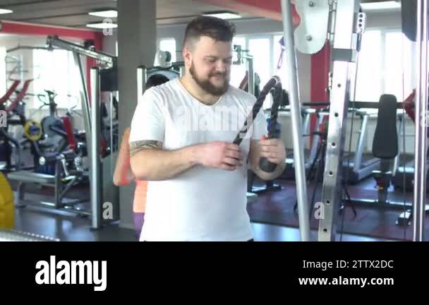 Bearded caucasian man works out in the gym with the help of the girls ...