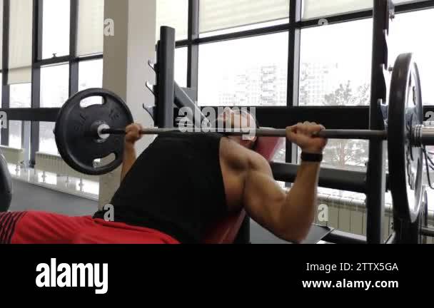 Young muscular man on bench press. Guy trains in the gym with a barbell ...