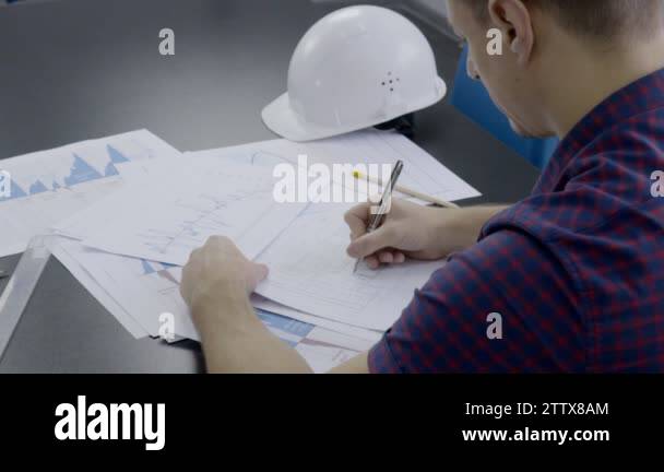 At desk there is an engineer working on a construction project on ...