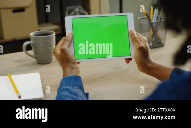 White tablet device being held by female hands horizontally. Green ...