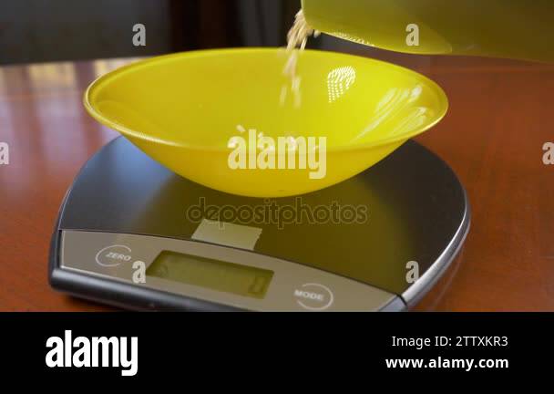 someone measures a piece of brown rice, on an electronic scale in the ...