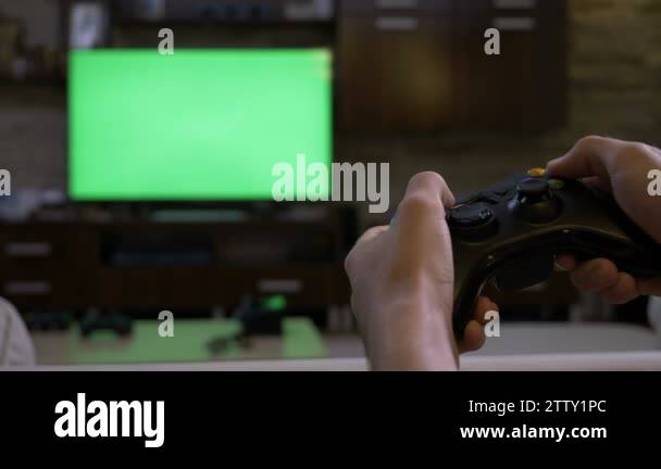 Man hands holding gamepad in front of chroma key green screen plasma ...