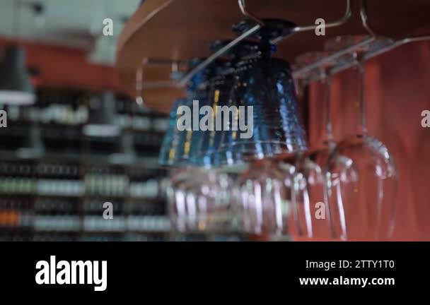 4K Clean wine glasses hanging upside down above a bar rack in ...