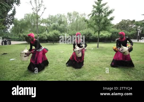Three african women dancing a folk dance in traditional costumes with ...