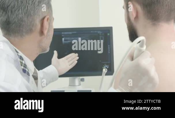 Doctor and patient sitting, looking at screen of monitor while doctor ...