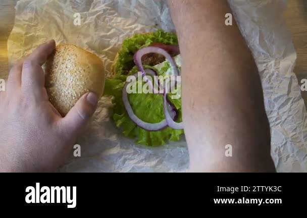 Fat man cooking and eating big hamburger in the kitchen, unhealthy ...