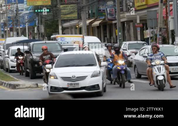 Motorbikes and cars drive along Asian roads. Traffic-laden Thai streets ...