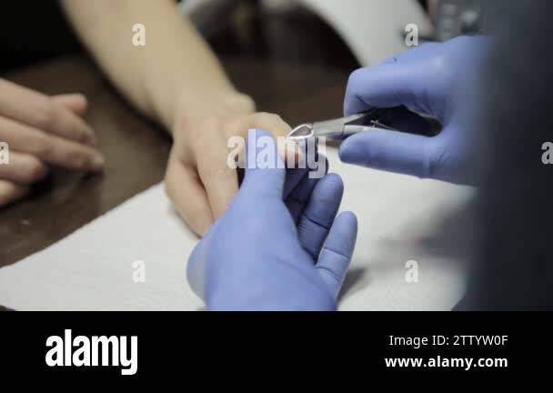 manicurist trimming the cuticle to womans manicured hand in nail salon ...