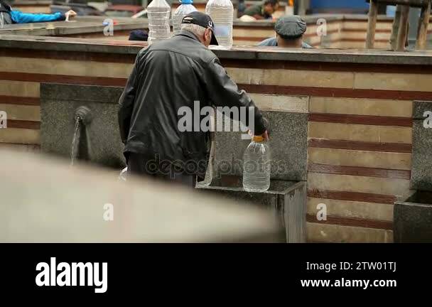 Local elderly men filling water tanks with mineral water, underground ...