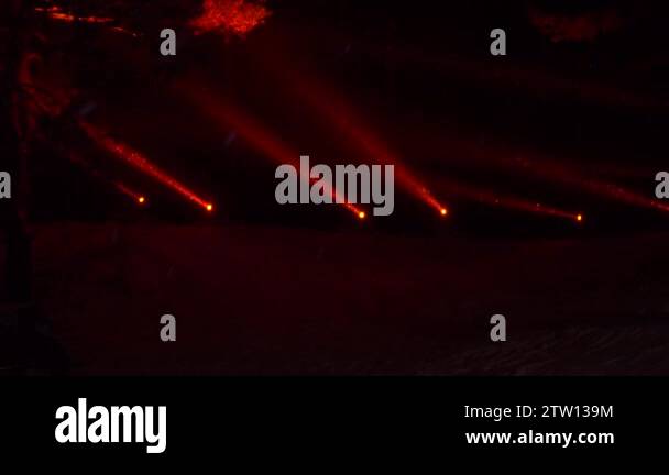 laser show with red beams in the night sky against falling snow ...