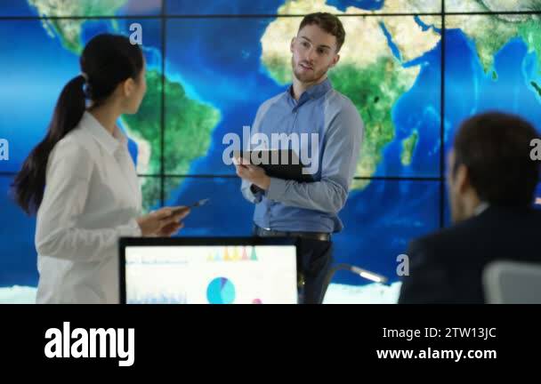 4K Business team discussing large world map graphic on video wall, with ...