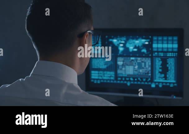 Back view of man programmer in glasses and white shirt working at ...