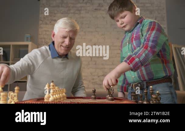 Grandfather and grandson are preparing to play chess. An elderly man ...