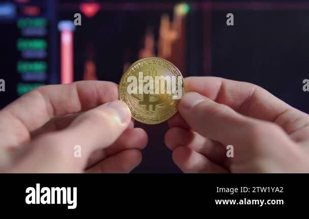 Male hands hold a gold coin bitcoin against the backdrop of a ...