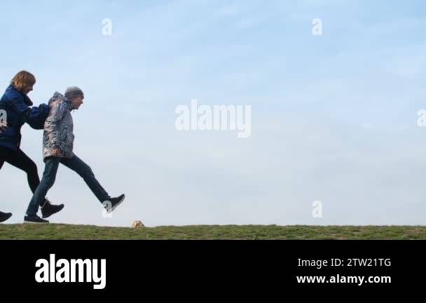 Funny view of a happy family marching on a flat meadow in spring in ...