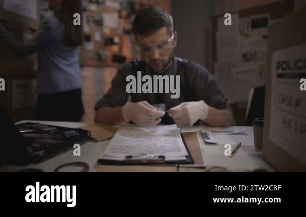 Ballistics officer comparing bullet size, examining evidence from ...