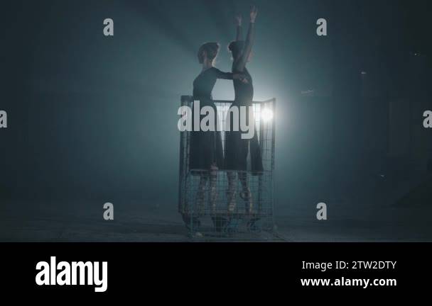 Two slim professional ballerinas dancing in black dress in the studio ...