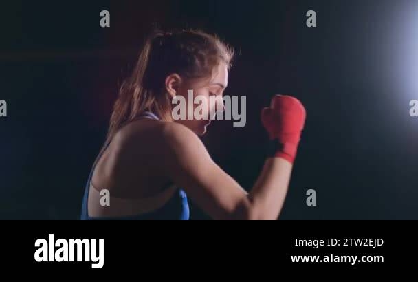 Female boxer training in dark room with backlight in slow motion side ...