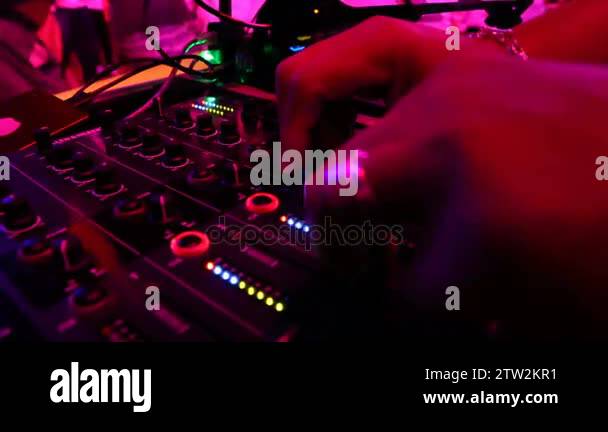 DJ Spinning, Mixing and Scratching in a Night Club, Hands of DJ tweak various track controls on ...