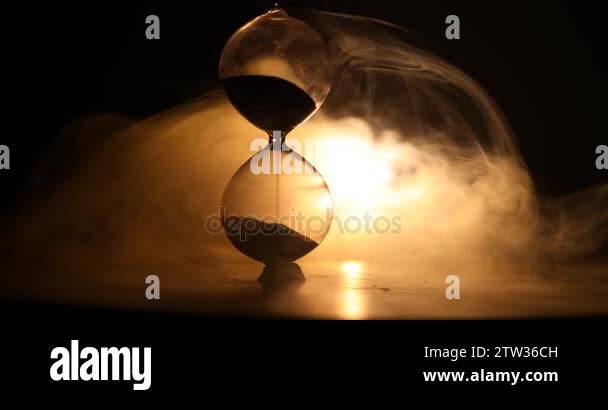 Time concept. Silhouette of Hourglass clock rotating in smoke on dark ...
