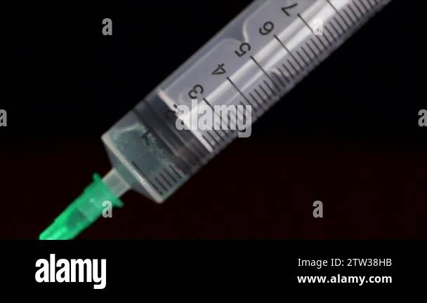 Medical syringe with liquid on black background. Water drop from ...