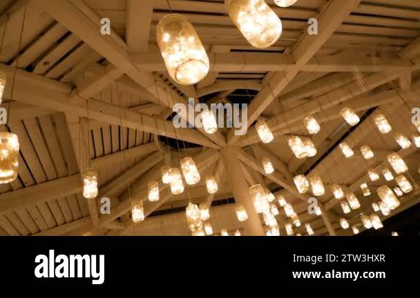 Self-made lanterns from cans are suspended on a wooden ceiling and ...