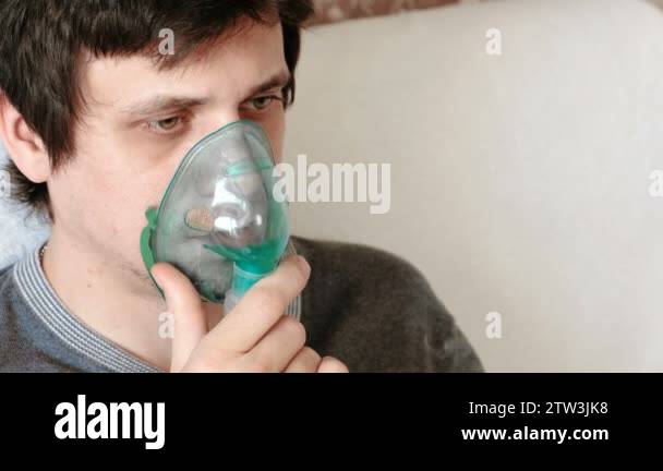 Use nebulizer and inhaler for the treatment. Closeup mans face inhaling ...