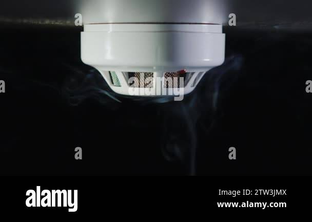 Smoke detector on a black background. There are trickles of smoke. The ...