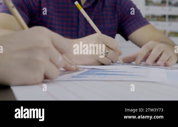 At desk two engineers draw a ruler and a pencil on sheet Stock Video ...
