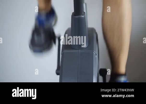 Man's working out on the exercise bike. Close up shot of cycle details ...