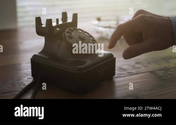 Man picking up the receiver and dialing a number on a vintage rotary ...