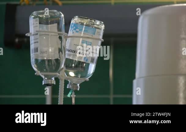 Two bottles of saline with dripping beads fixed to a drop counter in a ...