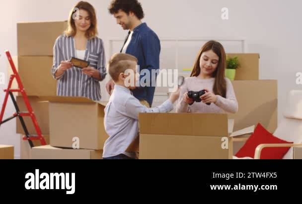 Two children unpacking a box with different home stuff while their ...