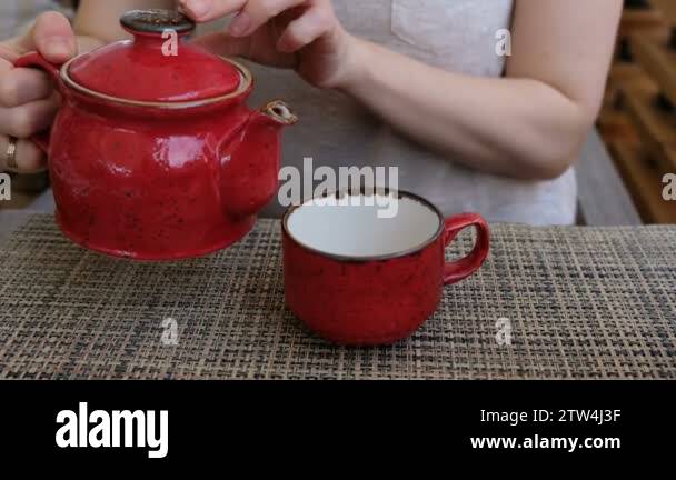 Hand that pours chinese green tea from ceramic kettle to smal cup ...