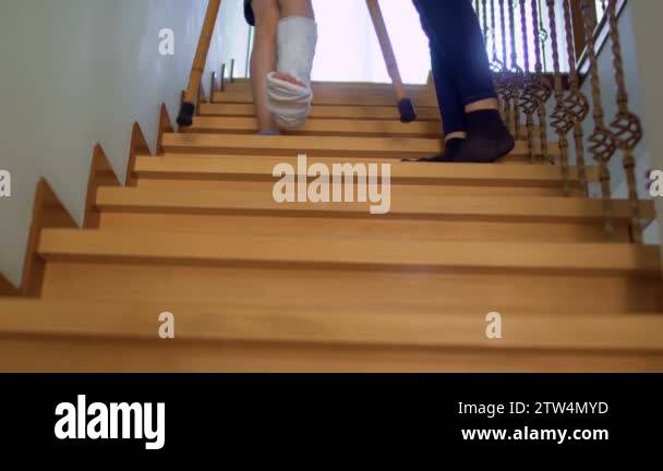 Mother help her son with broken leg to move down the stairs Stock Video ...
