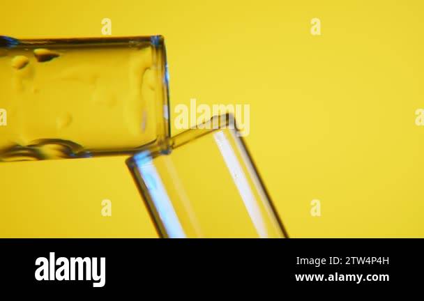 Clear fluid is poured from one tube into another in a chemical ...