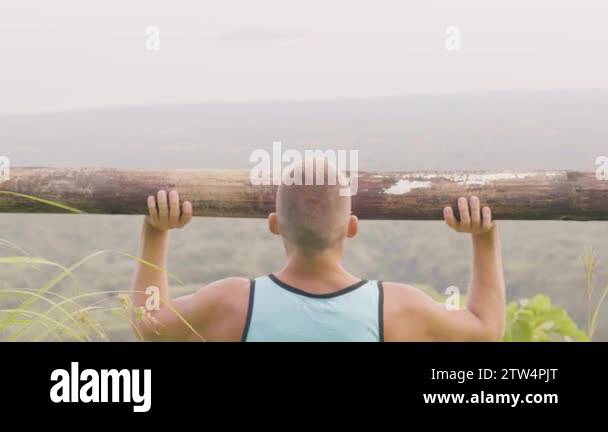 Athlete man lifting weight by wooden barbell while outdoor training ...