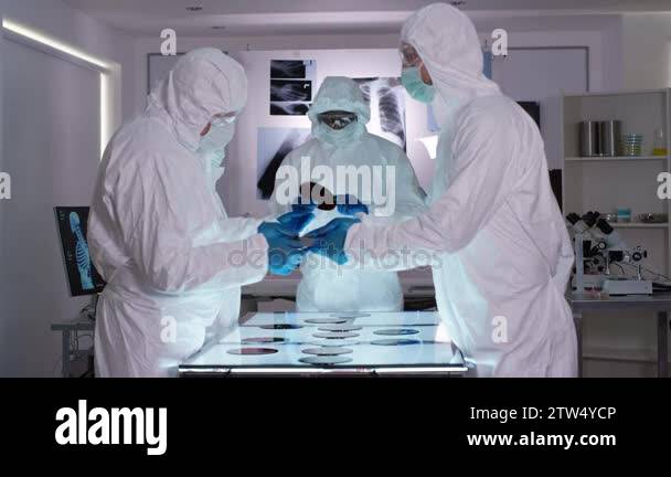 Scientific research team wearing full body suits examining hi-tech ...